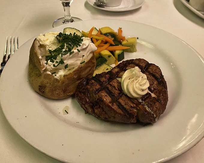 The classic steakhouse equation: one perfect filet, one loaded baked potato, and just enough vegetables to maintain the illusion of balance.