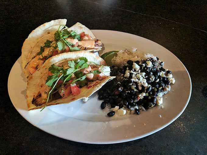 These aren't just fish tacos &ndash; they're flavor vessels sailing across a sea of black beans and rice, with cilantro as their proud flag.