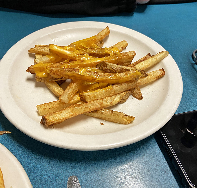 These aren't some fancy chef's "hand-cut potato batons" – they're proper diner fries, crispy on the outside, fluffy inside, with just enough cheese to make you forget your diet.