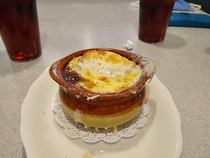 French onion soup that's dressed better than most people at a wedding. That melted cheese cap is the culinary equivalent of a warm hug.