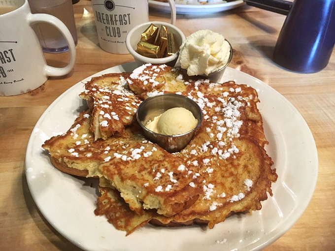 Golden-brown French toast dusted with powdered sugar, served with the kind of butter pat that makes margarine weep with inadequacy.