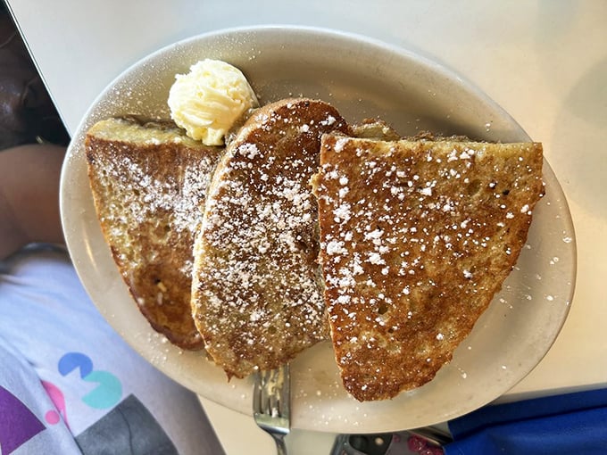 French toast dusted with powdered sugar like fresh snow on a mountain peak. That pat of butter melting on top? Pure breakfast poetry.