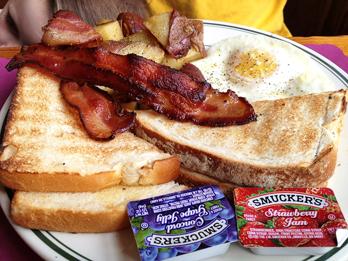 The breakfast trinity: golden French toast, bacon cooked to that magical point between chewy and crisp, and eggs that belong in the sunshine hall of fame.