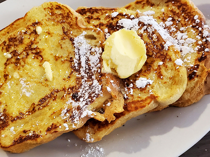 Golden-edged French toast that's crispy outside, custardy inside, with a melting pat of butter creating its own little yellow lake of deliciousness.