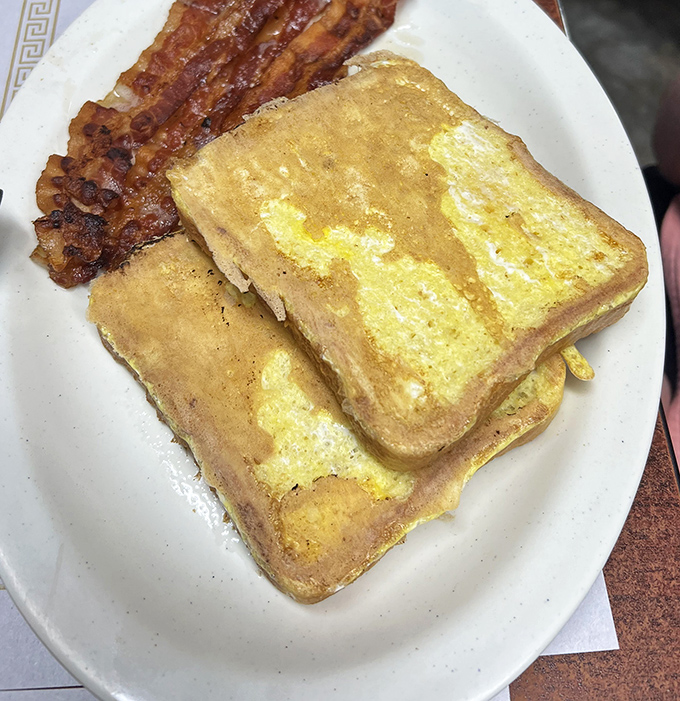 Golden French toast and perfectly crisped bacon &ndash; the breakfast of champions and hangover sufferers alike. Simple perfection on a white plate. 