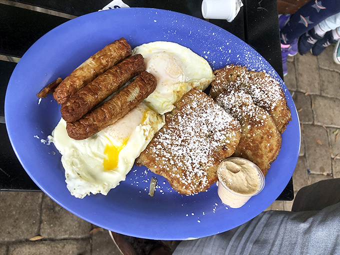 The holy trinity of breakfast indulgence: powdered sugar-dusted French toast, perfectly cooked eggs, and sausage links that would make even diet-conscious folks throw caution to the wind.