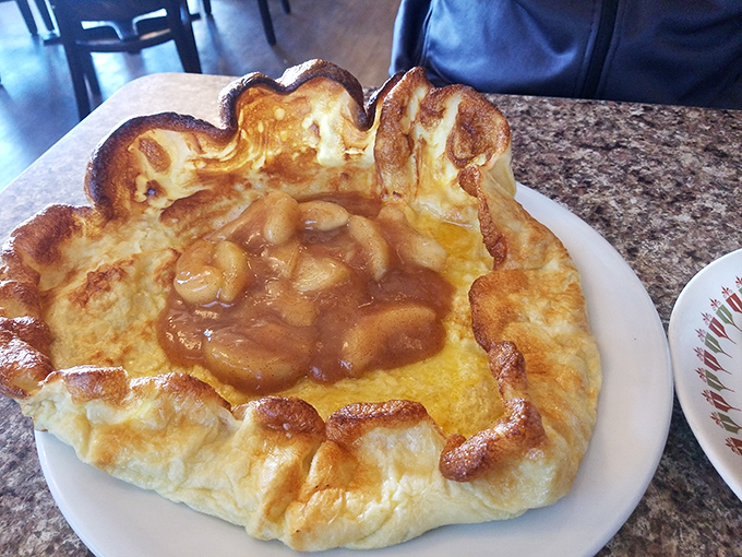 The German pancake rises like a souffle and cradles those cinnamon apples like they're precious cargo. Architectural marvel meets breakfast.