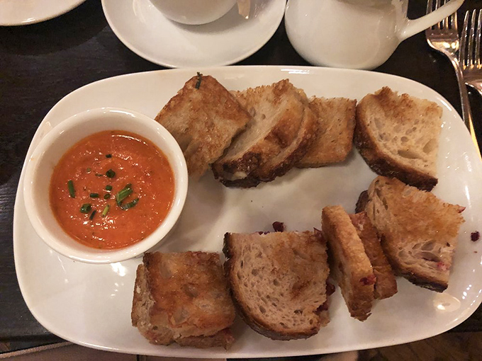 Grilled cheese elevated to art form&mdash;crusty artisanal bread flanking melted cheese with tomato soup for dipping. Childhood comfort meets grown-up sophistication.