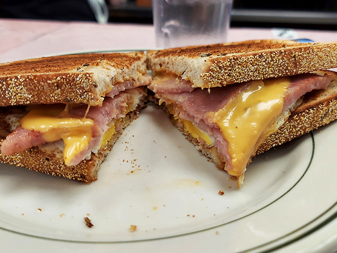 This isn't just a sandwich; it's architectural genius. Perfectly toasted sesame bread cradles melty cheese and ham in breakfast harmony.