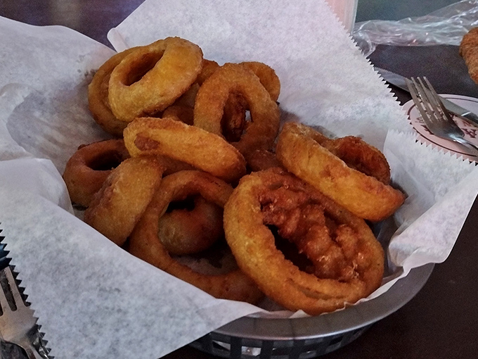 These onion rings arrive stacked like golden halos, proving that sometimes heaven is deep-fried and served in a basket.