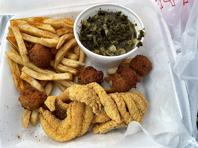 A perfect Southern trinity: crispy catfish, seasoned fries, and collard greens that would make your grandmother nod in silent approval.