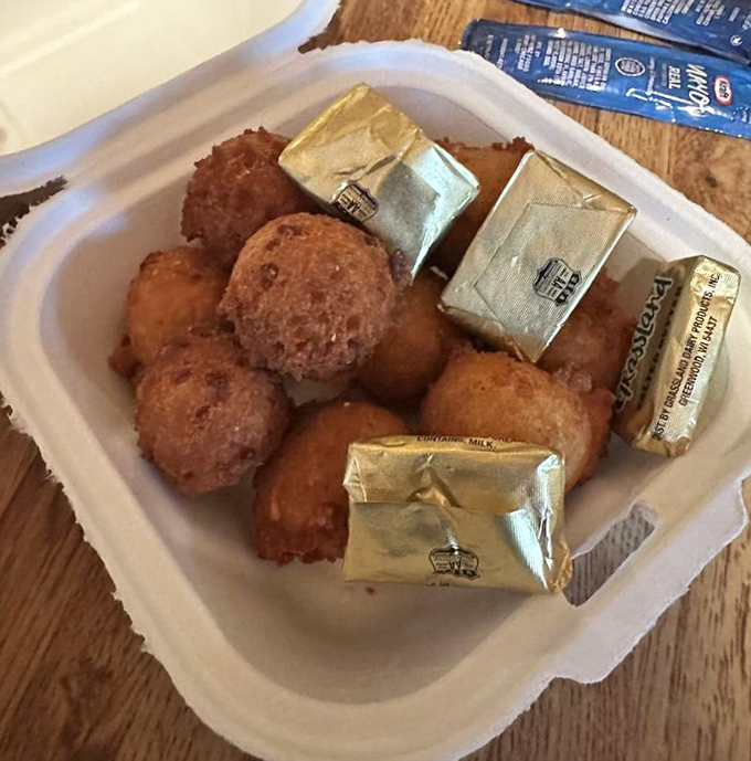 Golden-brown hush puppies, crispy outside and tender inside, arrive with butter packets standing by like little soldiers ready for duty.