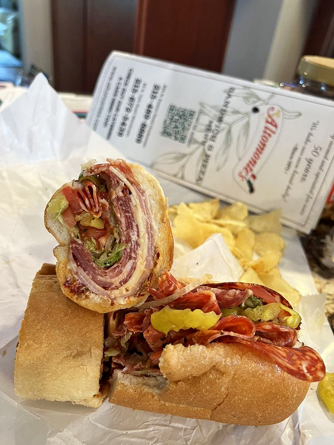 The Italian hoagie in its natural habitat: wrapped in paper, cut in half, revealing its glorious stratification of meats, cheese, and toppings.