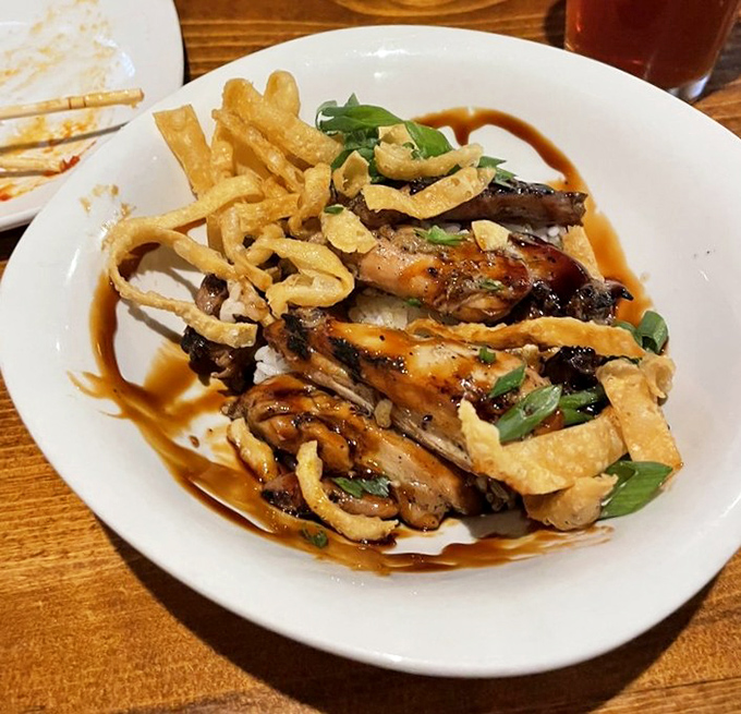 Korean BBQ chicken that would make Seoul proud—glazed thighs nestled on rice with crispy wontons standing guard like delicious sentinels.