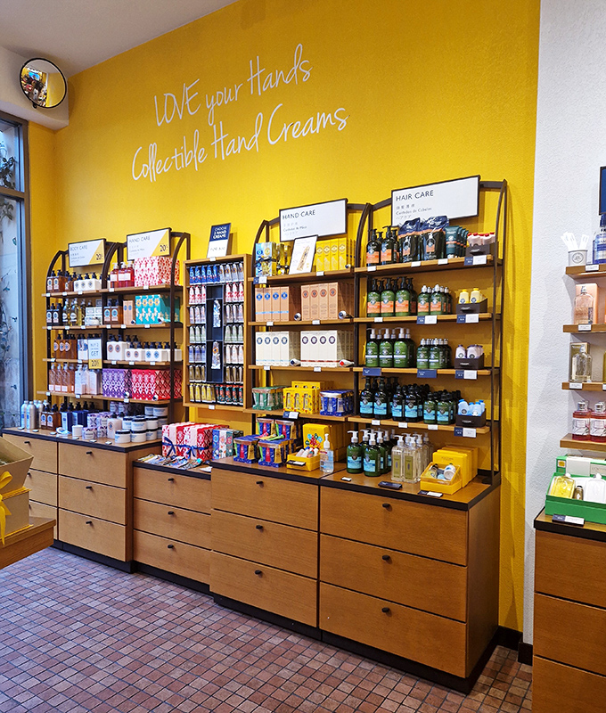 L'Occitane's vibrant yellow wall showcases hand creams that promise to rescue your skin from a day of shopping bag handles.