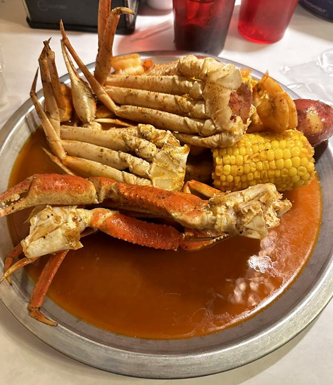 Snow crab legs, corn, and potatoes swimming in seasoned sauce &ndash; a metal tray treasure chest that rewards those willing to work for their dinner.