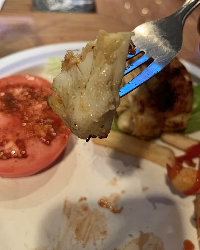 Each forkful reveals what makes Maryland crab cakes legendary—sweet jumbo lump meat barely held together by what seems like wishful thinking and a prayer.