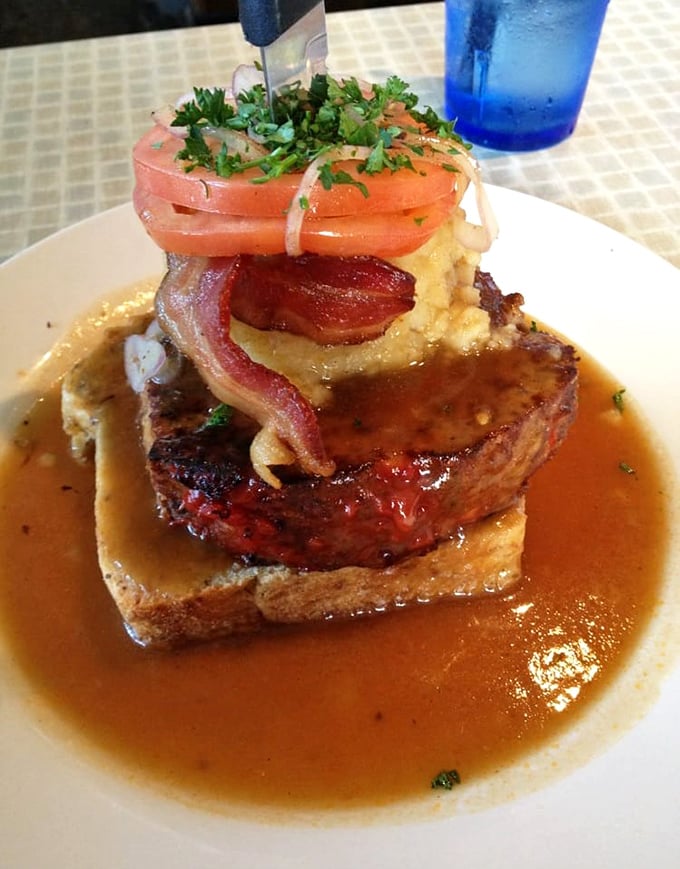 Meatloaf elevated to art form: a tower of savory goodness swimming in rich gravy, topped with mashed potatoes and fresh tomato&mdash;comfort food reaching for the stars.