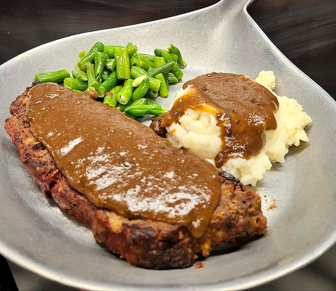 Comfort on a plate: tender meatloaf smothered in rich gravy alongside cloud-like mashed potatoes and green beans that somehow make you feel virtuous.