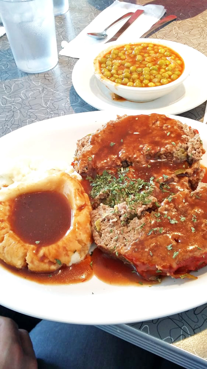 Meatloaf that would make your grandmother simultaneously proud and jealous, swimming in a tomato gravy that deserves its own fan club.