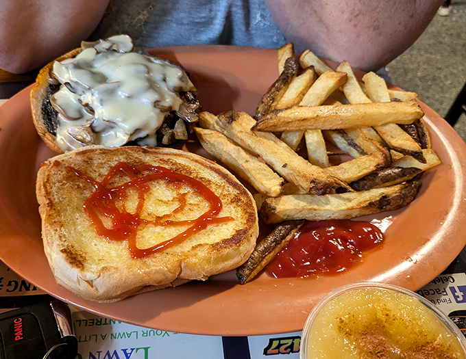 The mushroom Swiss burger arrives like a savory still life&mdash;golden fries standing at attention beside their beefy commander. Ketchup art included at no extra charge.