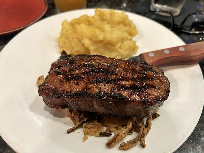 Behold the star attraction: a perfectly seared New York Strip with textbook grill marks, accompanied by mashed potatoes that aren't just an afterthought.