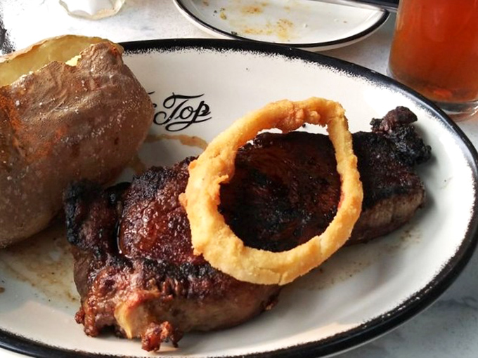 A steak that demands respect, accompanied by an onion ring so perfect it deserves its own spotlight.