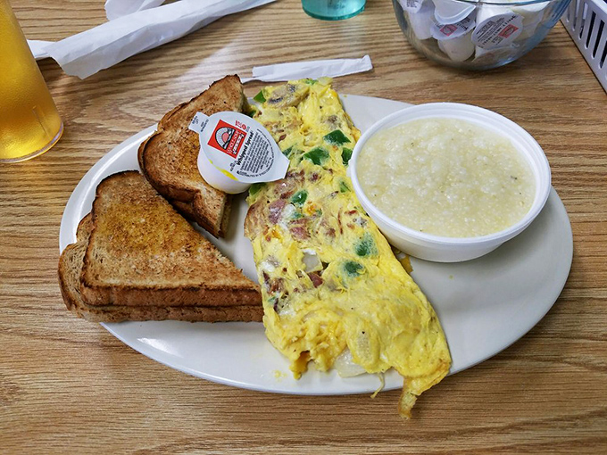 This omelet doesn't just contain ingredients; it embraces them in a fluffy yellow hug, while those buttery grits stand by as the perfect sidekick.