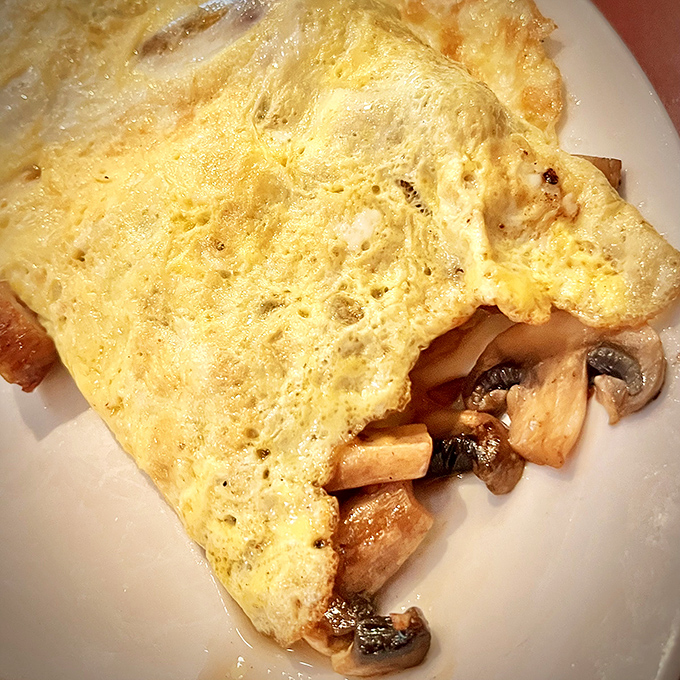 An omelet so fluffy it could double as a pillow, crowned with mushrooms that actually taste like mushrooms.