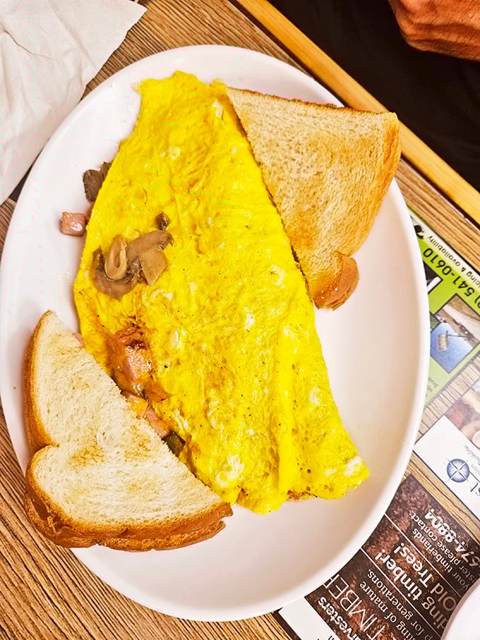 This omelet defies gravity with its fluffy height, stuffed with mushrooms and ham like a savory treasure chest.