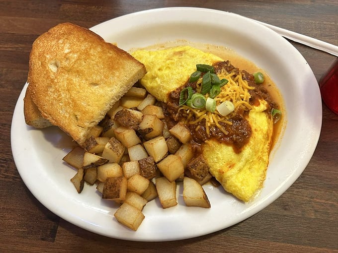 This isn't just any omelet – it's a masterclass in the art form. Perfectly folded sunshine yellow exterior giving way to savory fillings, with those crispy homefries standing guard.