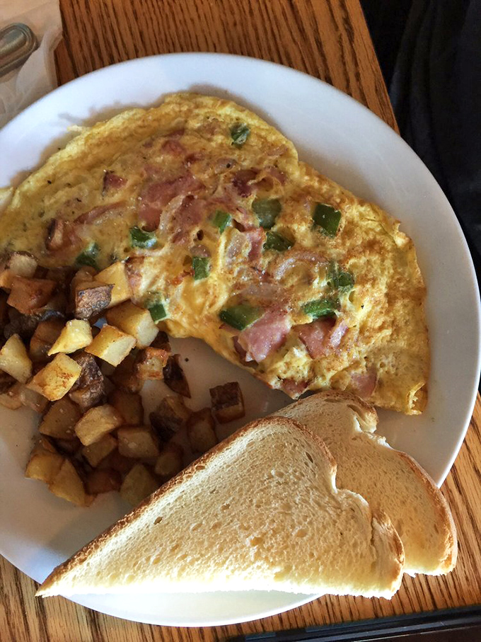 Breakfast perfection: a ham and veggie omelet that's fluffy enough to make clouds jealous, alongside home fries that redefine potato potential.