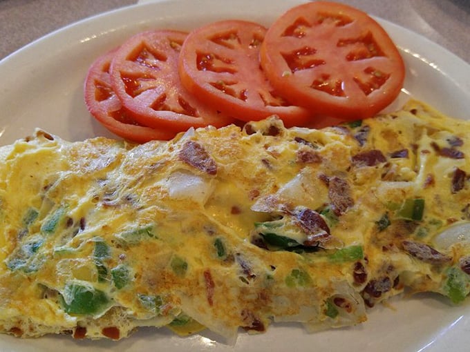 This omelet arrives looking like sunshine on a plate, with those perfect tomato slices adding a pop of color.