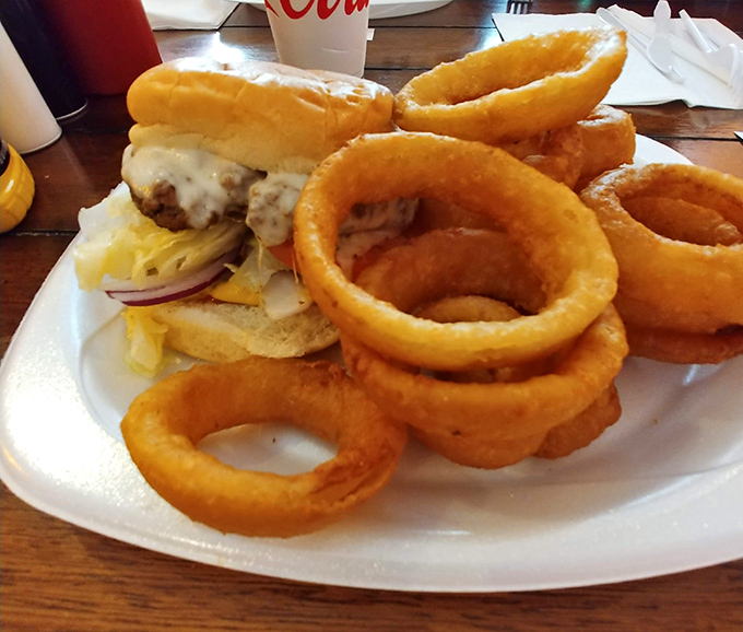 Onion rings that could double as golden halos, surrounding a burger that demands a two-handed commitment. This is why elastic waistbands were invented.