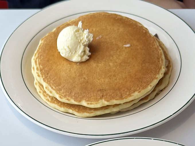 Golden pancakes so perfectly round they'd make geometry teachers weep, topped with a butter pat melting like a summer romance.