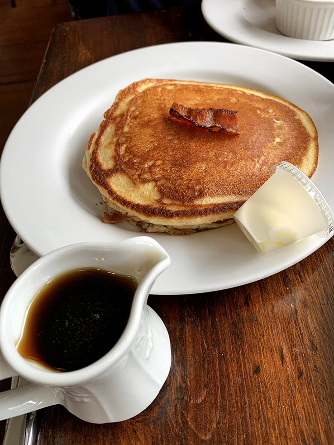 Pancakes so perfectly golden they make you wonder if the chef has a degree in breakfast architecture. That bacon strip? Just showing off.