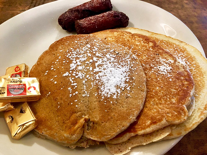 These golden pancakes aren't just breakfast, they're an edible postcard from carb heaven, dusted with powdered sugar and flanked by perfect sausage links.