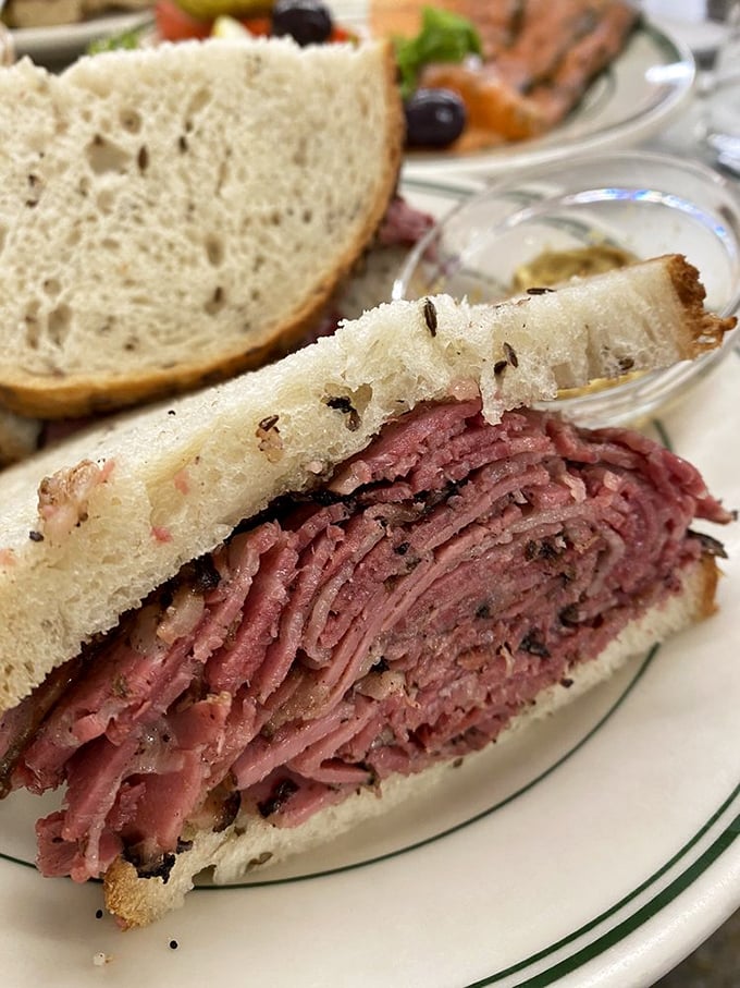 Architecture in sandwich form: layers of hand-sliced pastrami stacked with mathematical precision between rye bread bookends. Skyscraper eating at its finest.