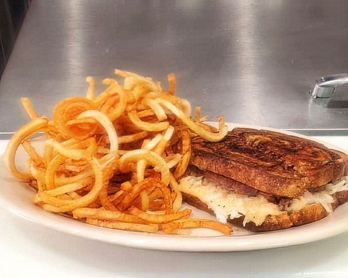 Curly fries that look like they're doing the cha-cha next to a sandwich that's been grilled with the kind of attention usually reserved for fine art.