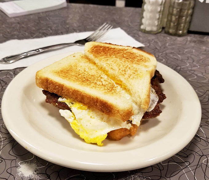 Breakfast sandwich perfection: crispy toast, melty cheese, eggs with that perfect yolk, and bacon that would make a vegetarian question their life choices.