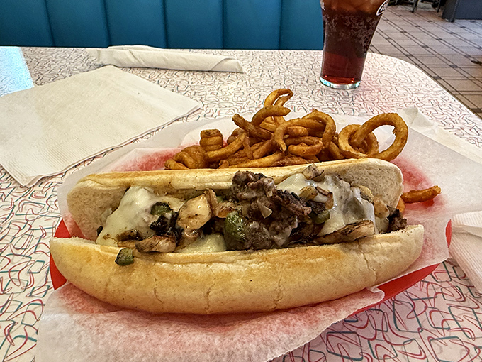 This Philly cheesesteak arrives with a side of onion rings, because sometimes more really is more.