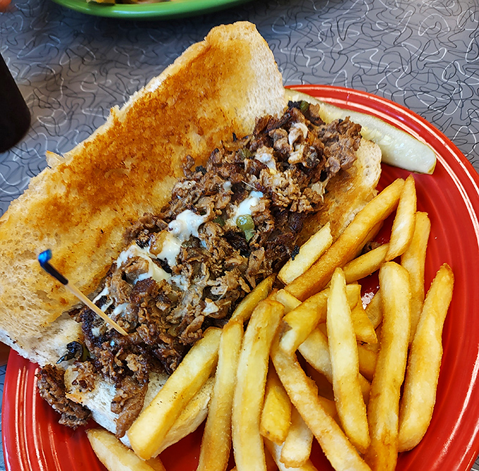 This Philly cheesesteak sandwich isn't messing around – perfectly toasted bread, savory meat, melted cheese, and those golden fries deserve their own fan club.