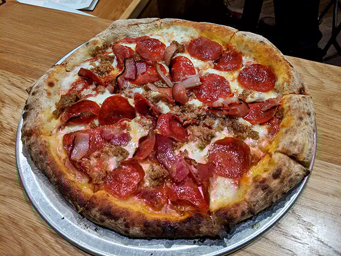 Pizza perfection: a leopard-spotted crust supporting the holy trinity of pepperoni, sausage, and that cheese pull that haunts your dreams.
