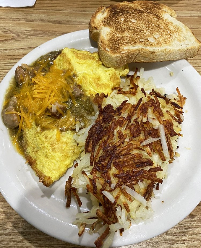 This omelet doesn't just sit on the plate—it commands attention with its golden exterior and generous filling. Hash browns crisped to perfection.