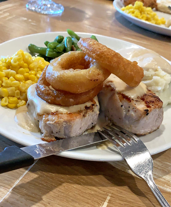 The pork chop arrives like a work of art&mdash;topped with crispy onion rings that serve as both garnish and the perfect excuse for finger food. 