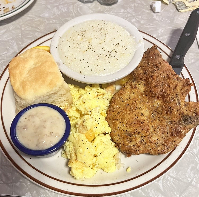 A breakfast plate that means business: fluffy eggs, perfectly seasoned country fried steak, creamy grits, and a biscuit that would make your grandma jealous.
