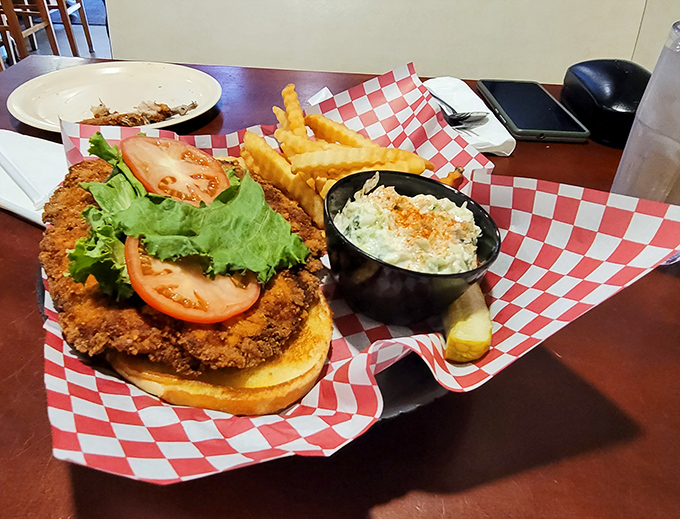 This breaded pork tenderloin sandwich refuses to acknowledge the boundaries of its bun, flanked by crispy fries and creamy coleslaw for the perfect Iowa trifecta.