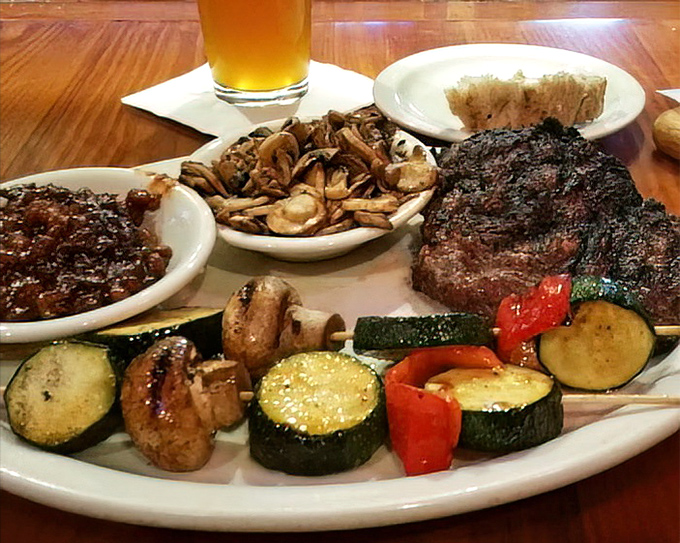 A plate that tells a story of perfect balance: juicy steak, saut&eacute;ed mushrooms, grilled vegetables, and is that a beer I spot? The four food groups of happiness.
