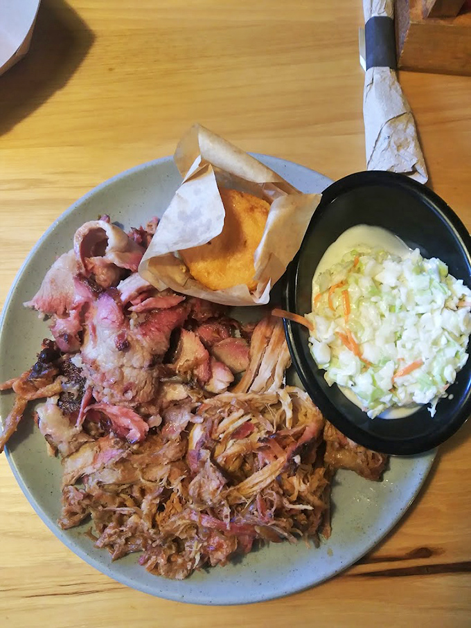 This plate tells the story of Southern comfort: pulled pork in all its glory, cornbread nestled in paper, and coleslaw standing by for that perfect bite balance.