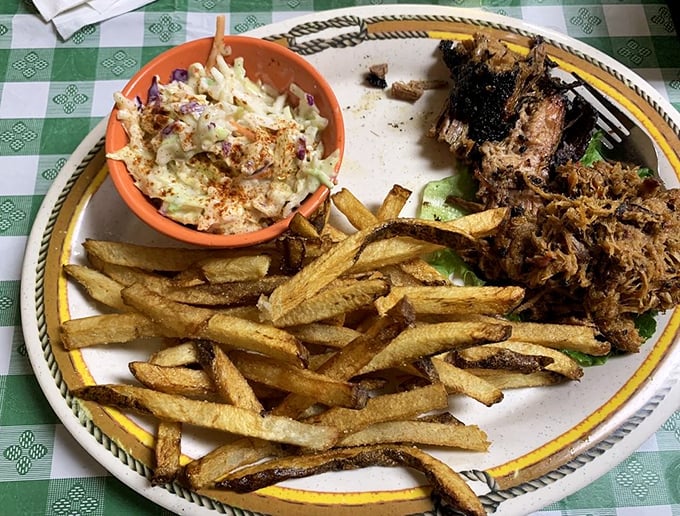 A plate that speaks the universal language of comfort: golden fries, creamy slaw, and pulled pork with a bark so beautiful it deserves its own art exhibition.